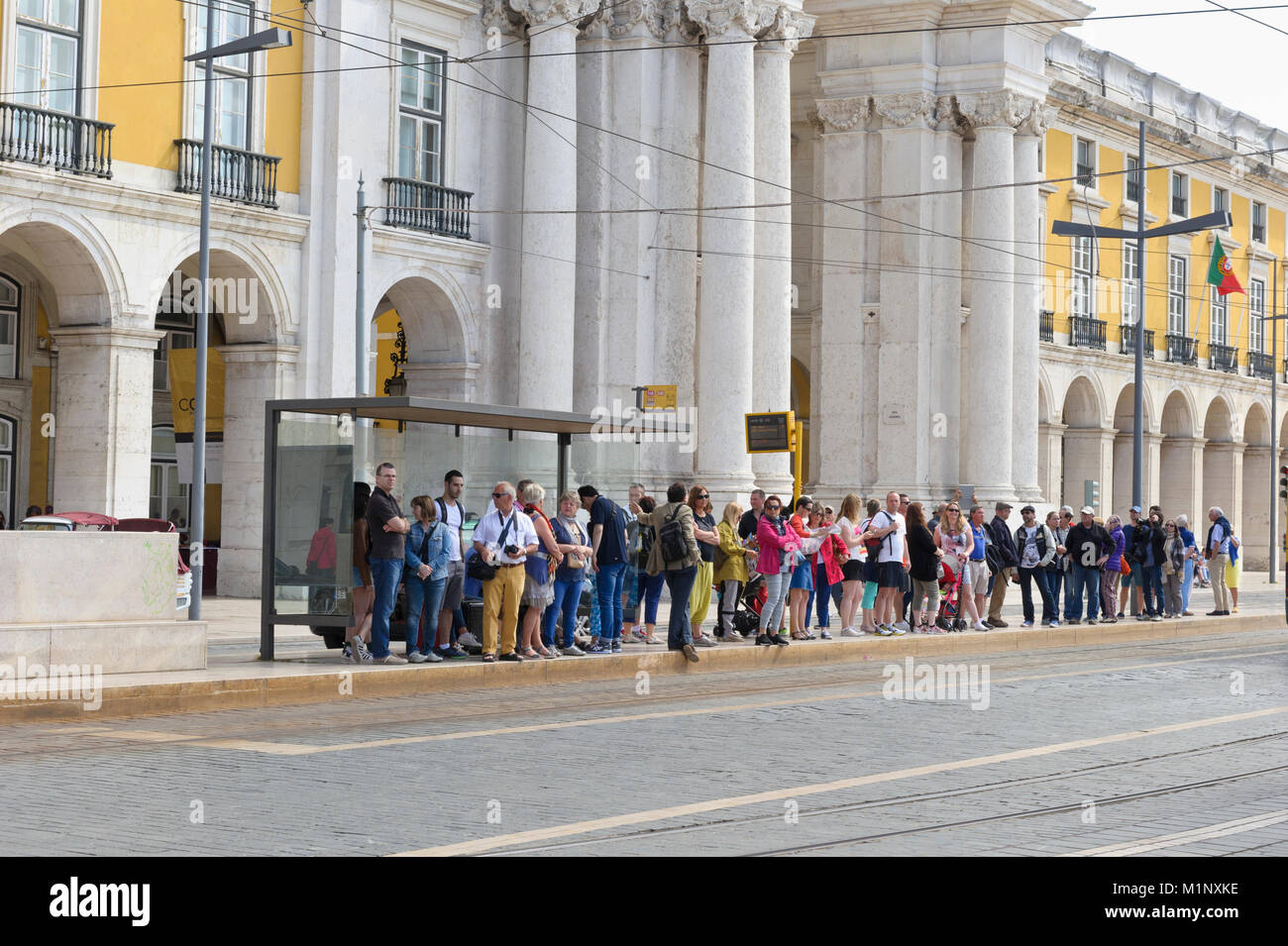 A long queue of people waiting for the arrival of the electric tram ...