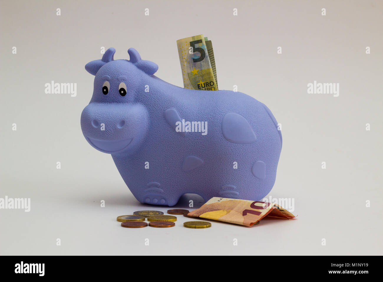 money box cow, with Euro banknotes and coins on a white background ...