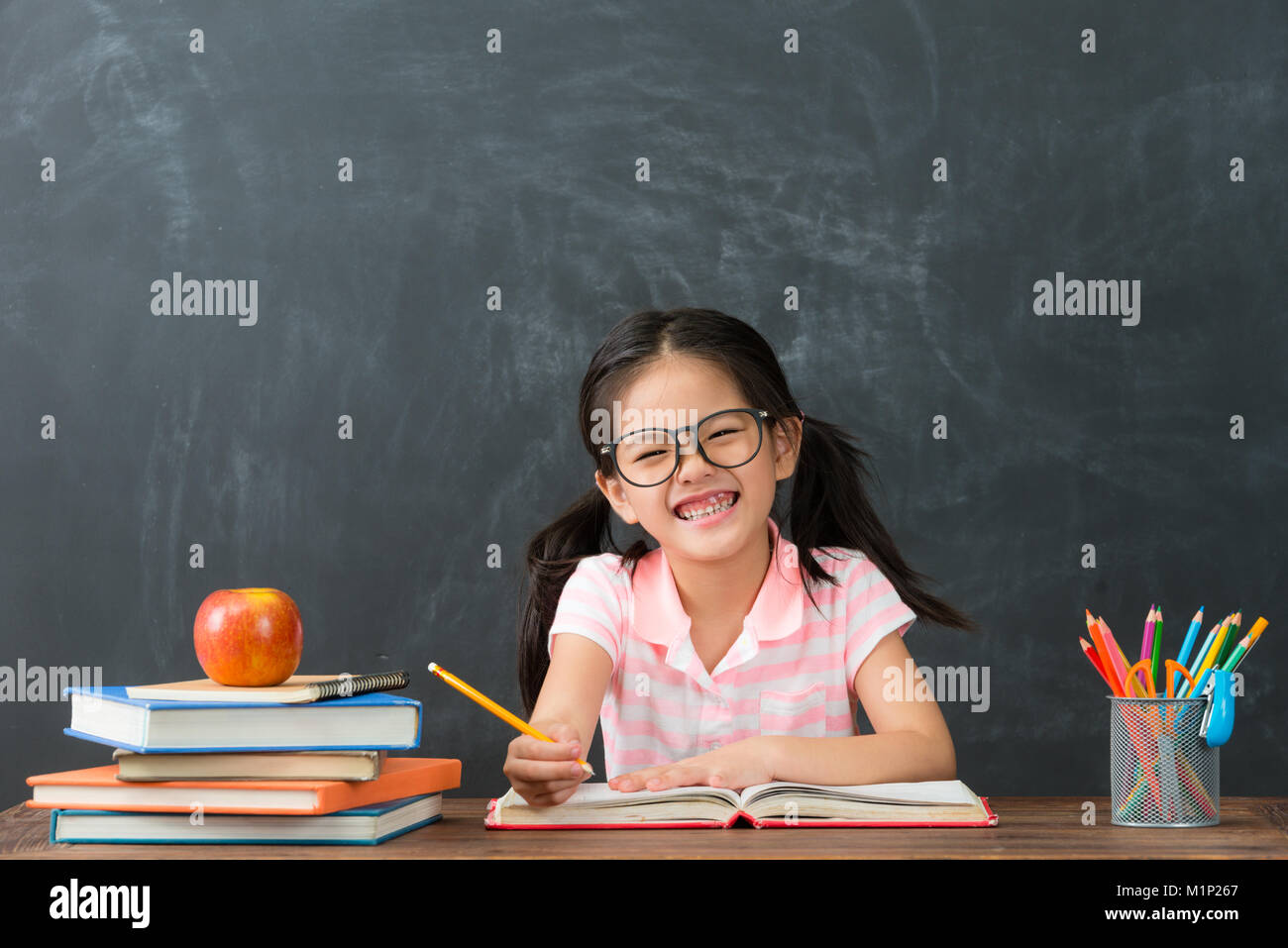 happy cheerful female student doing homework in class on chalkboard ...