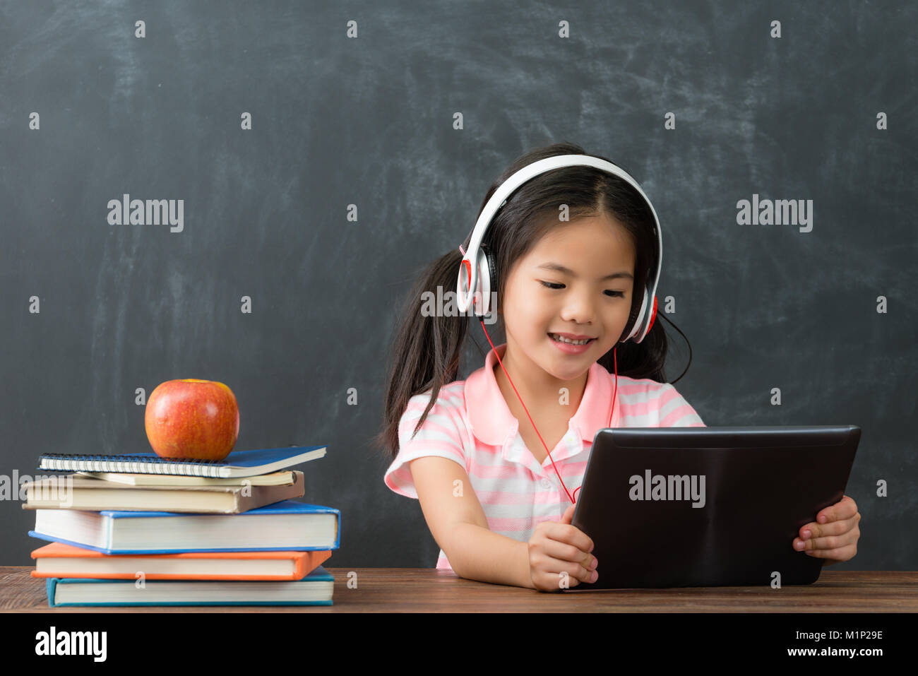 happy beautiful little girl student sitting in blackboard background ...