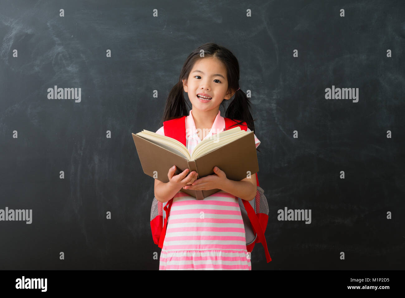 happy beautiful female kid student back to school studying and holding ...