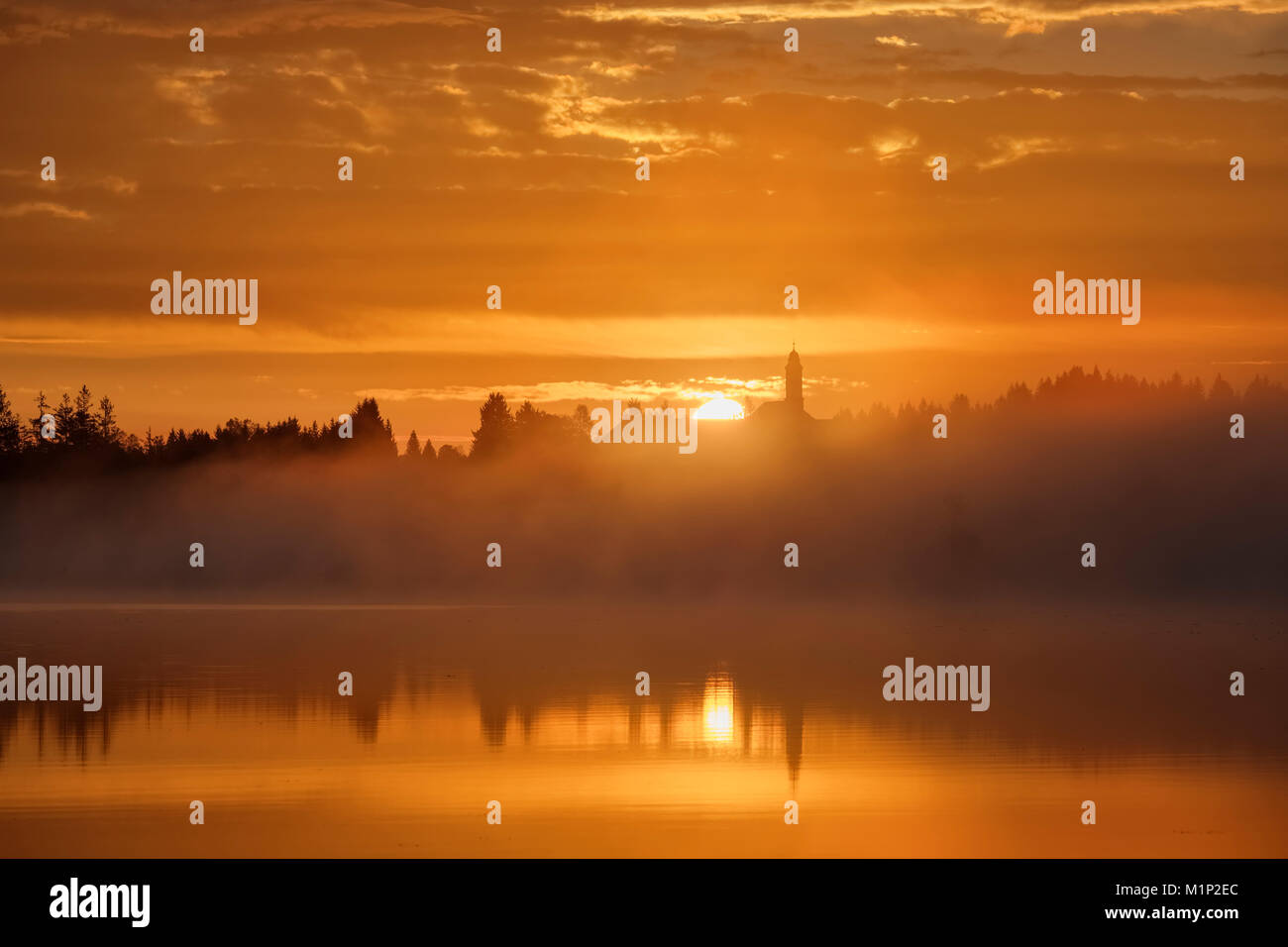 Sunrise,early morning mist over Kirchsee with Reutberg Monastery ...