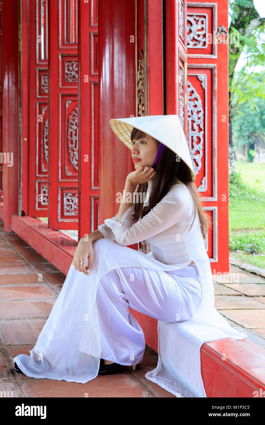 A woman in a traditional Ao Dai dress and Non La conical hat in the Forbidden Purple City of Hue ...