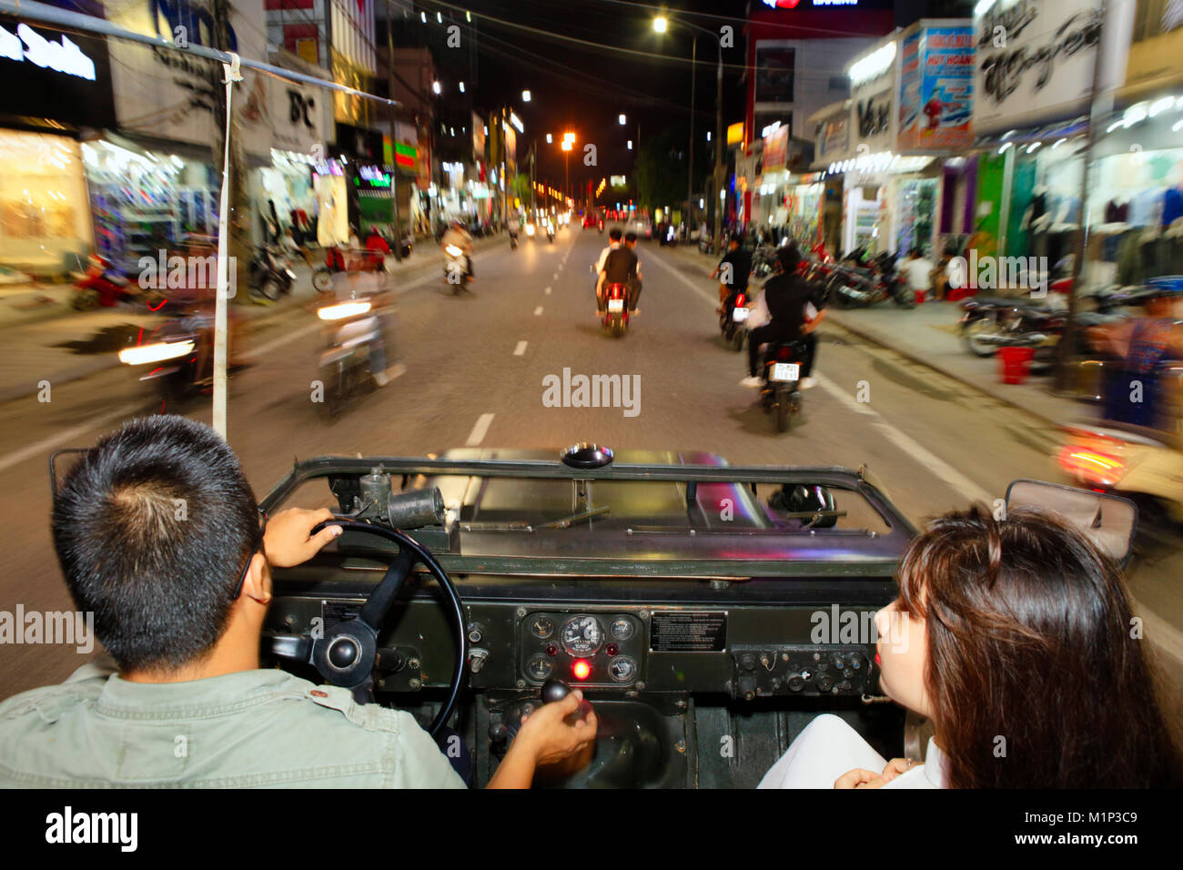 A Vietnamese couple in an open-top Jeep driving through the streets of ...