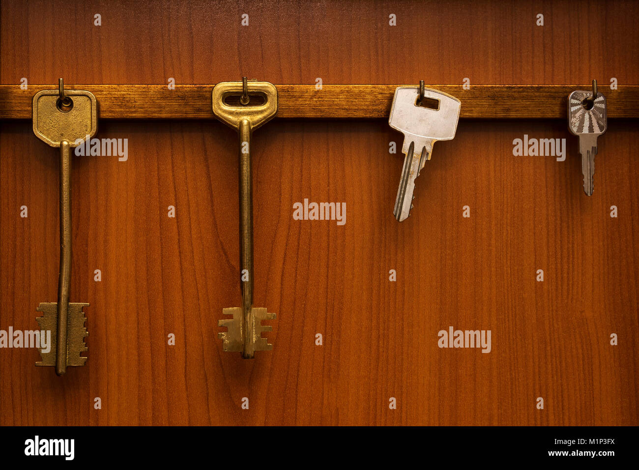 Keys hanging on a wall. On a wooden background Stock Photo - Alamy