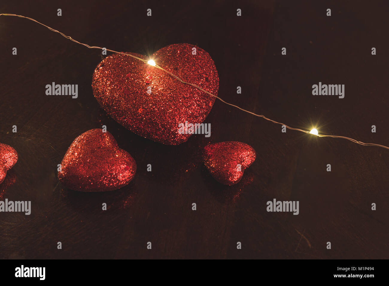 Big red hearts with other smaller red hearts laying on top of a wooden ...
