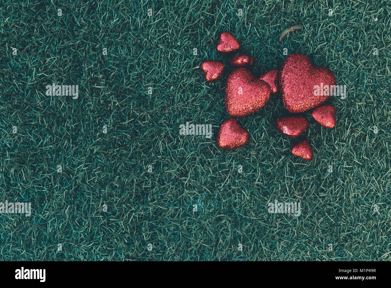 Multiple red hearts bunch up together on top of green grass leaving ...