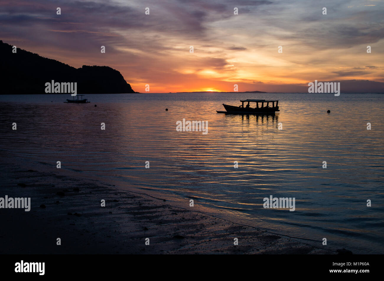Magical sunset with traditional boat at a deserted beach near surf spot ...