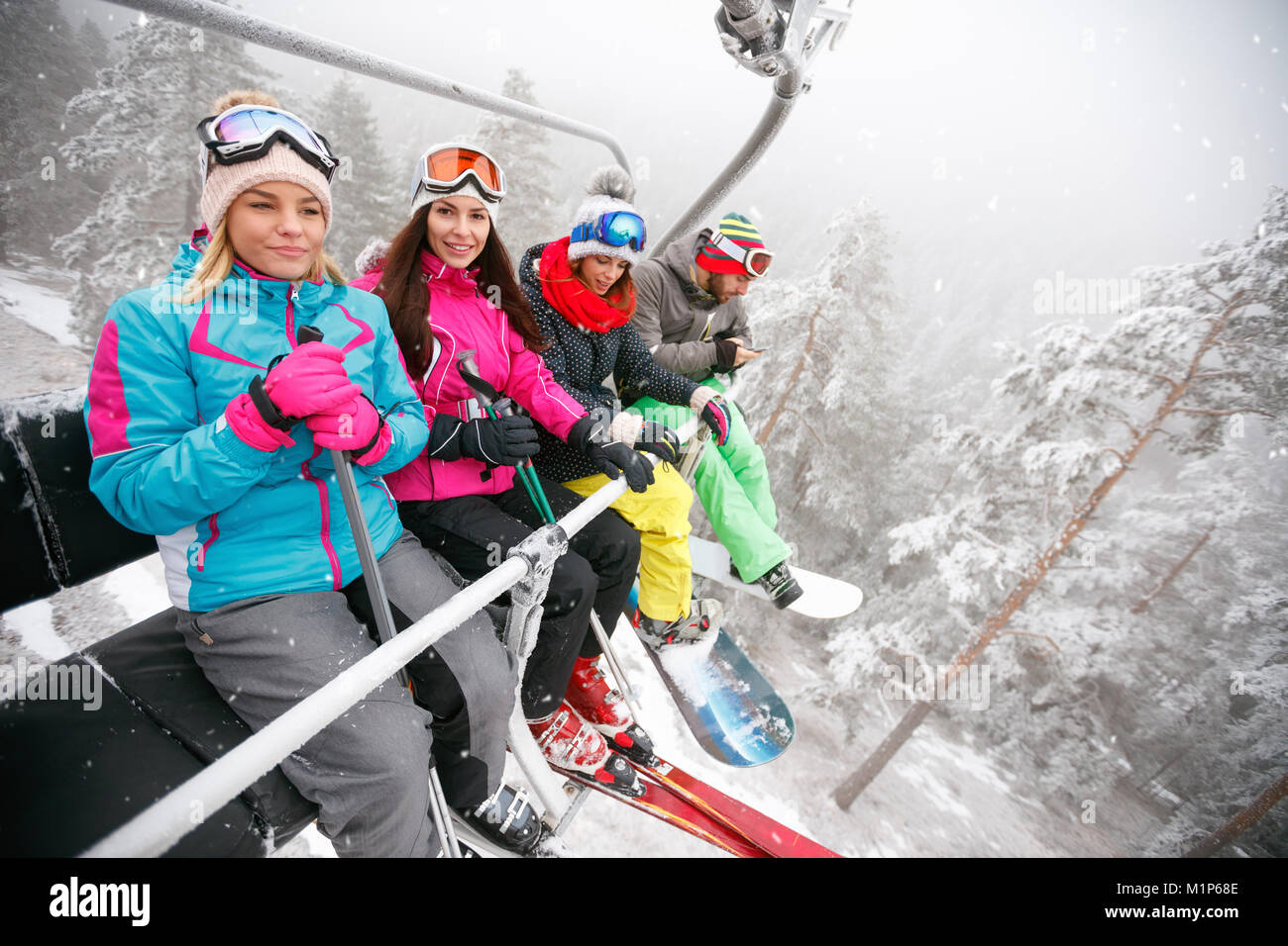 young friends on ski lift ride up on snowy mountain Stock Photo - Alamy