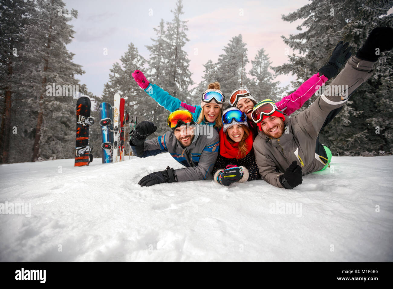 Enjoying in beautiful winter day- young skiers lying on snow and having ...
