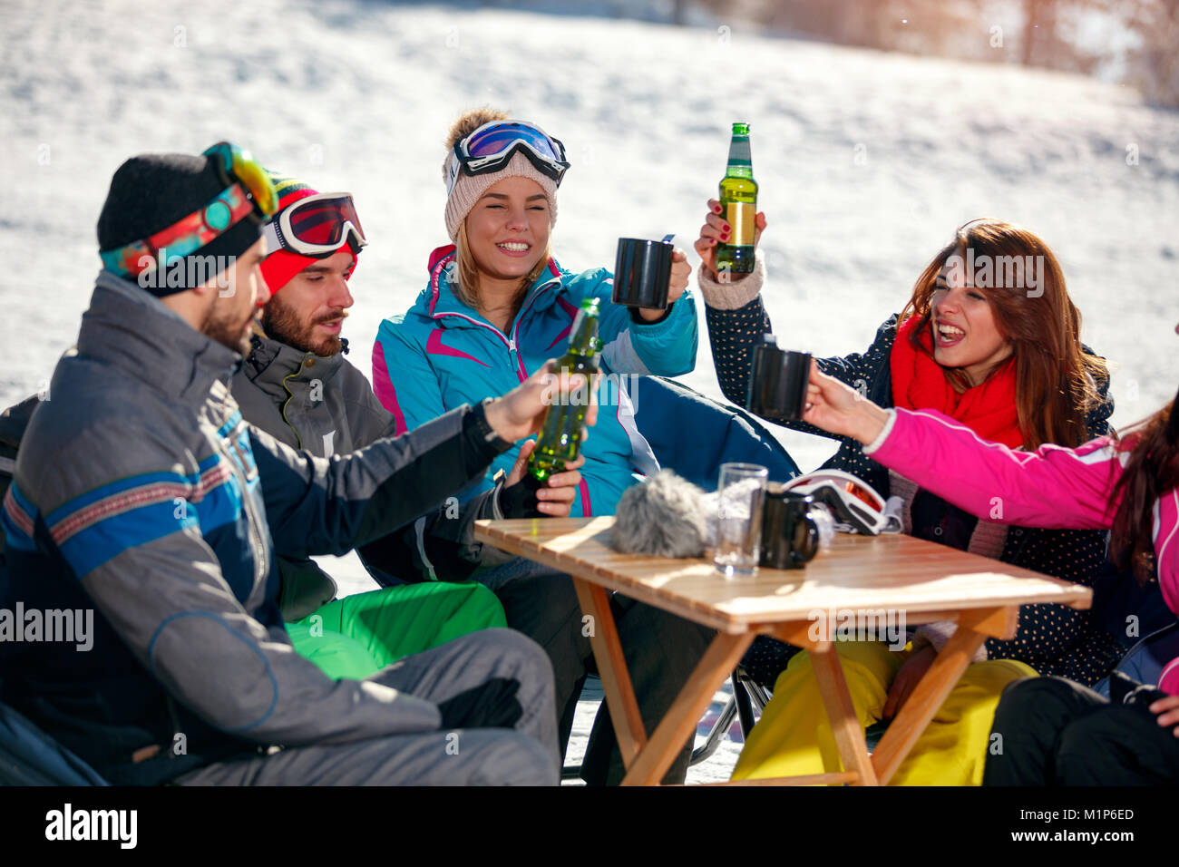 Group of happy friends cheering with beer after skiing day in cafe at ...