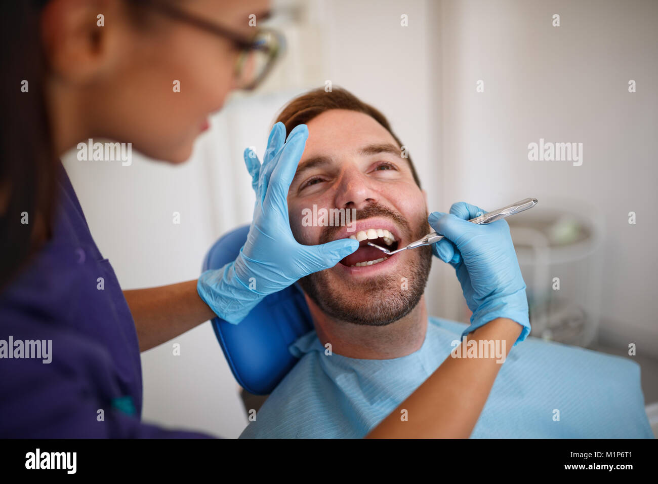 Dentist checking up patient’s teeth with dental mirror in ordination ...