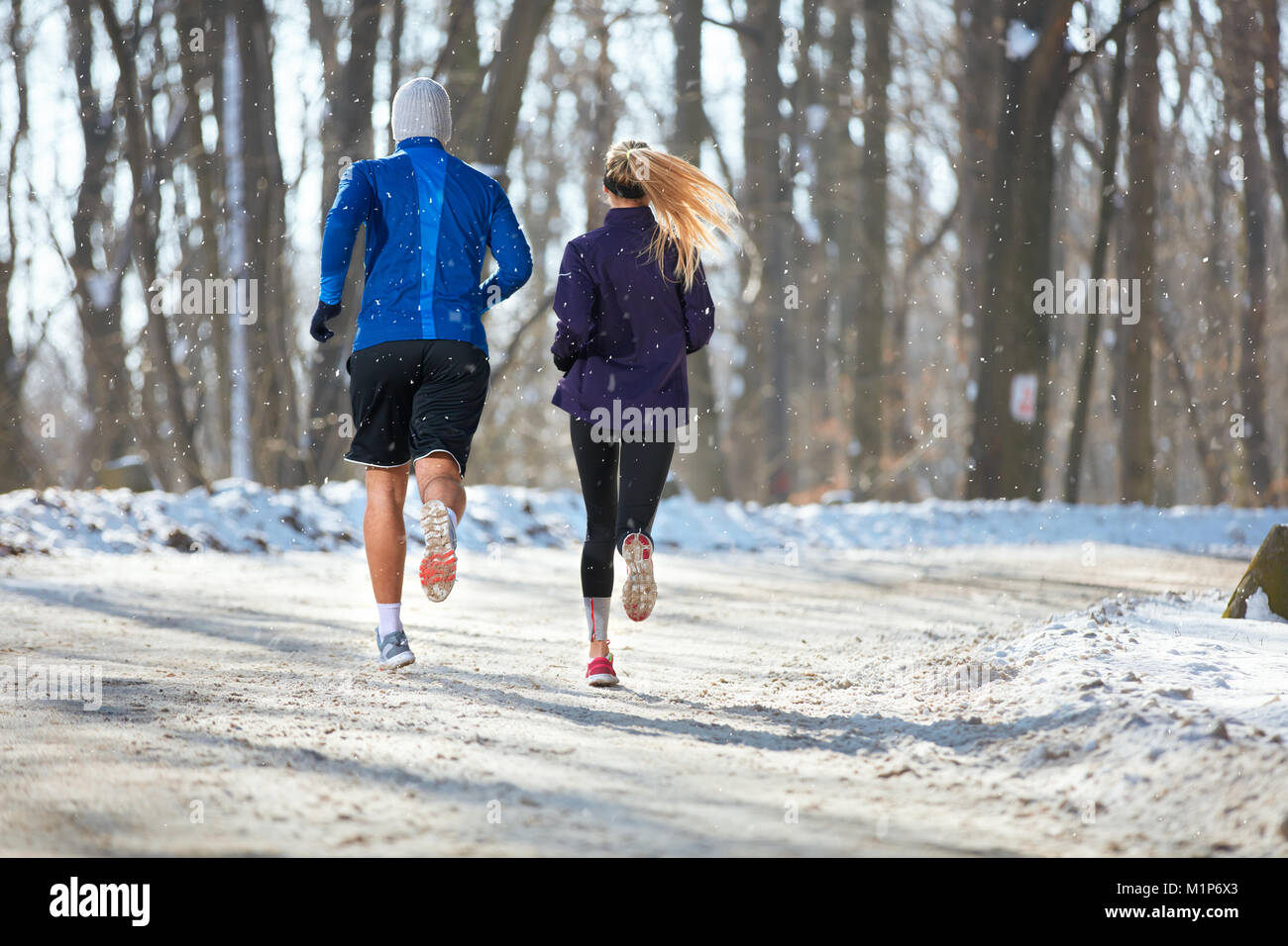 Young male and female jogging in nature at winter, back view Stock ...