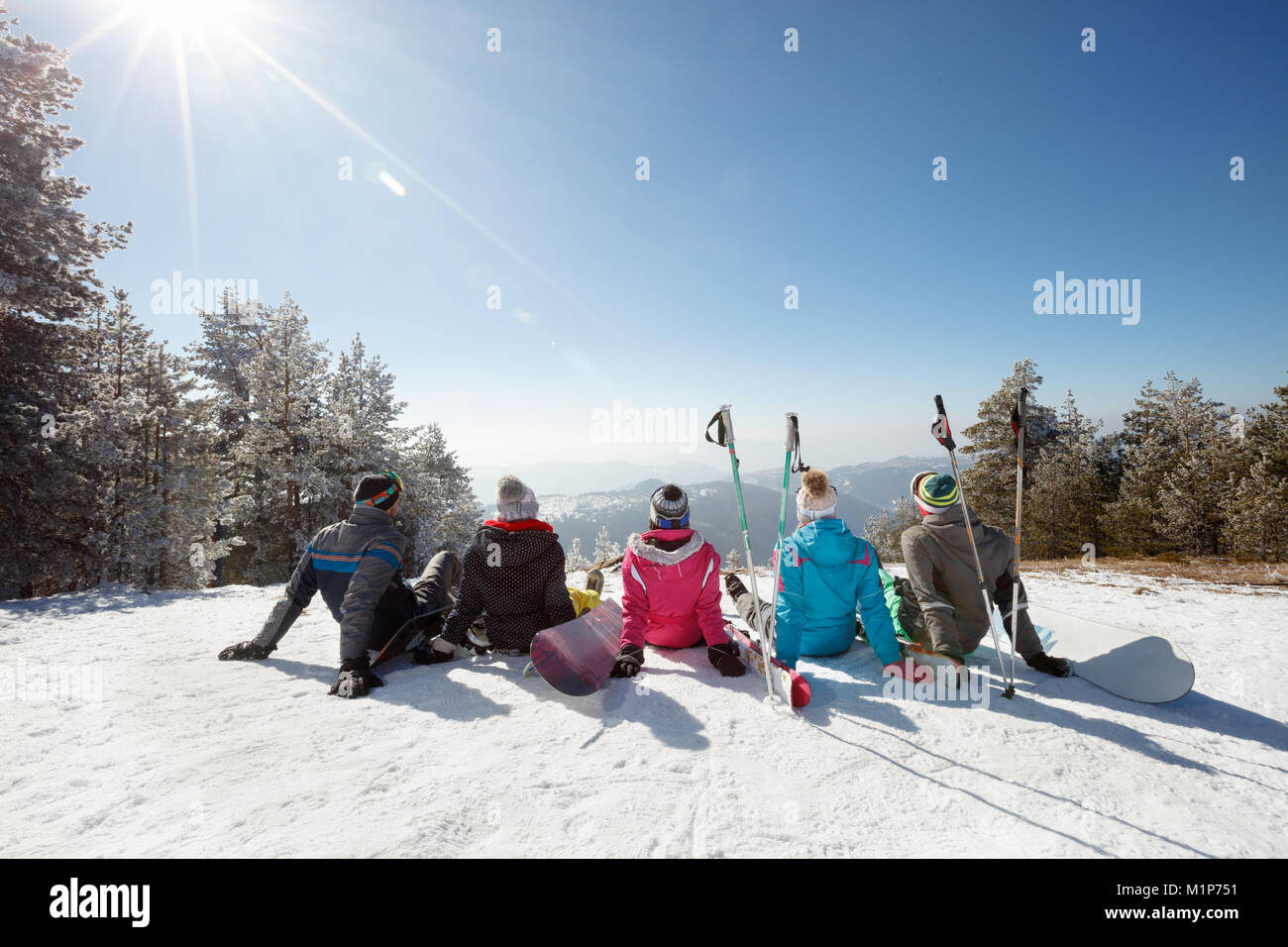 Skiers sitting on snow and looking landscape on skiing in mountain ...