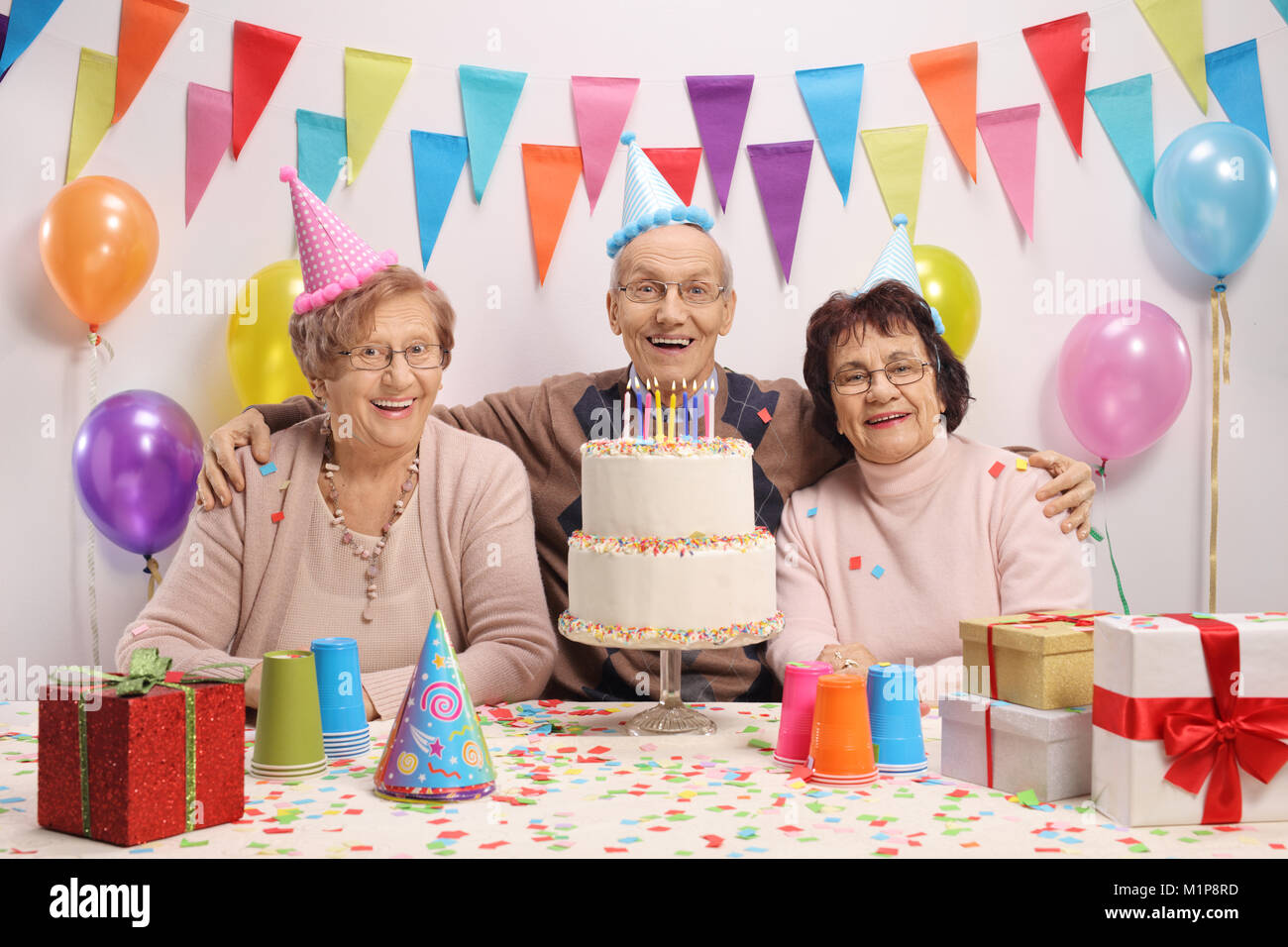 Happy seniors with a cake and party hats celebrating a birthday Stock ...