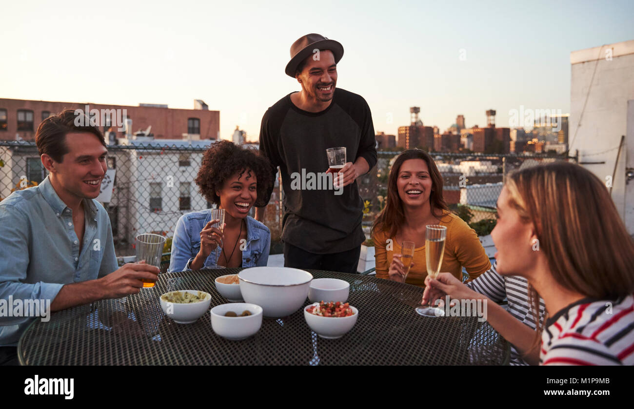 Six adult friends laughing at a table on a rooftop, close up Stock ...