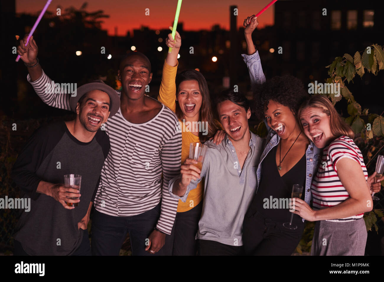 Happy friends waving glowsticks at rooftop party in Brooklyn Stock ...