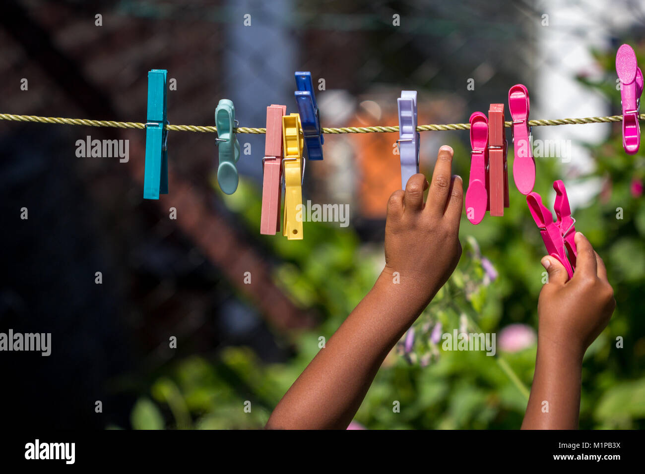 A young child playing with clothes pegs and a washing line in the ...