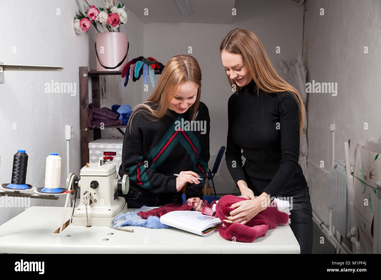 Two young women furriers are discussing how to properly cut natural fur ...