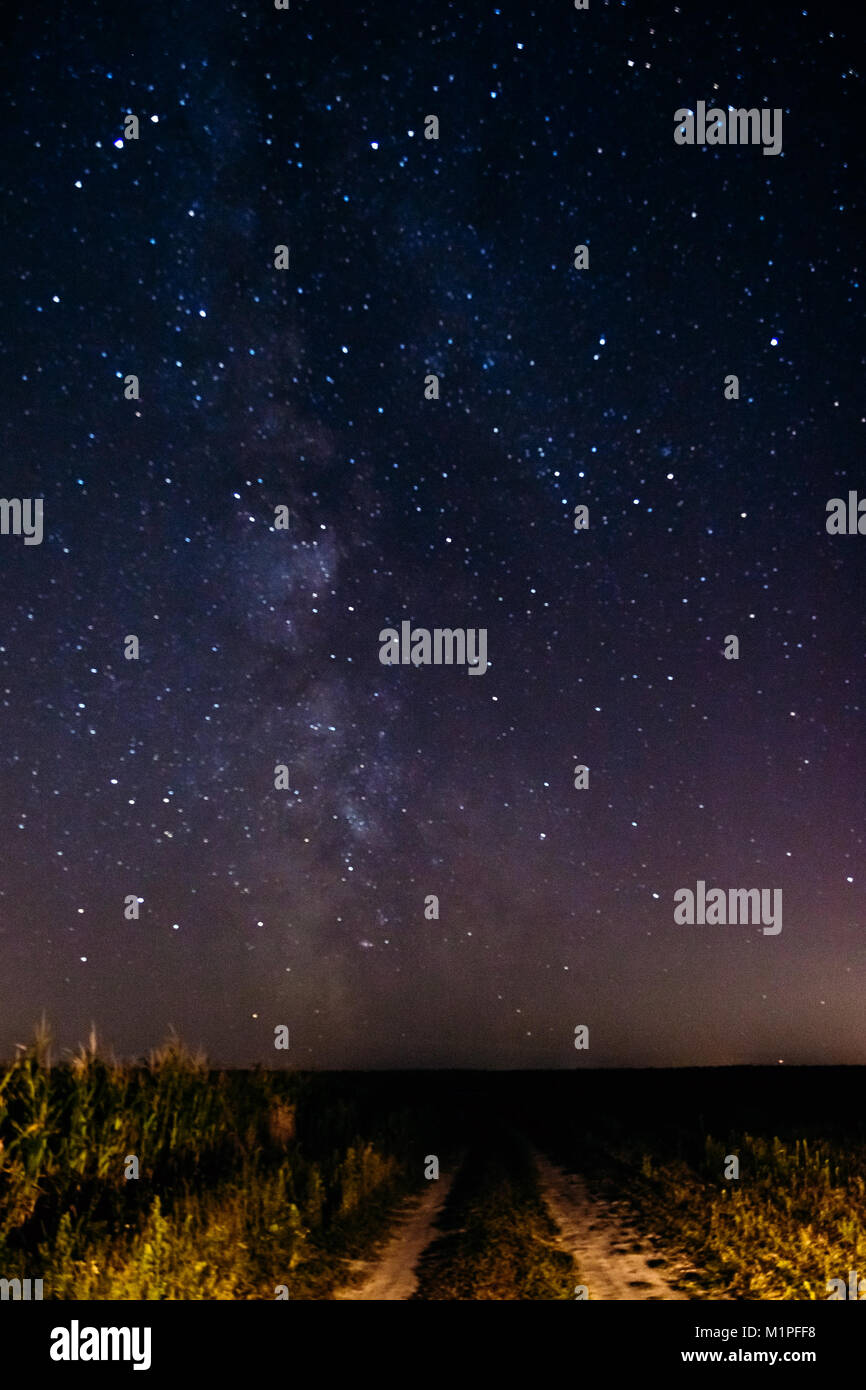 Starry sky with the Milky Way on it over the field with rural road ...