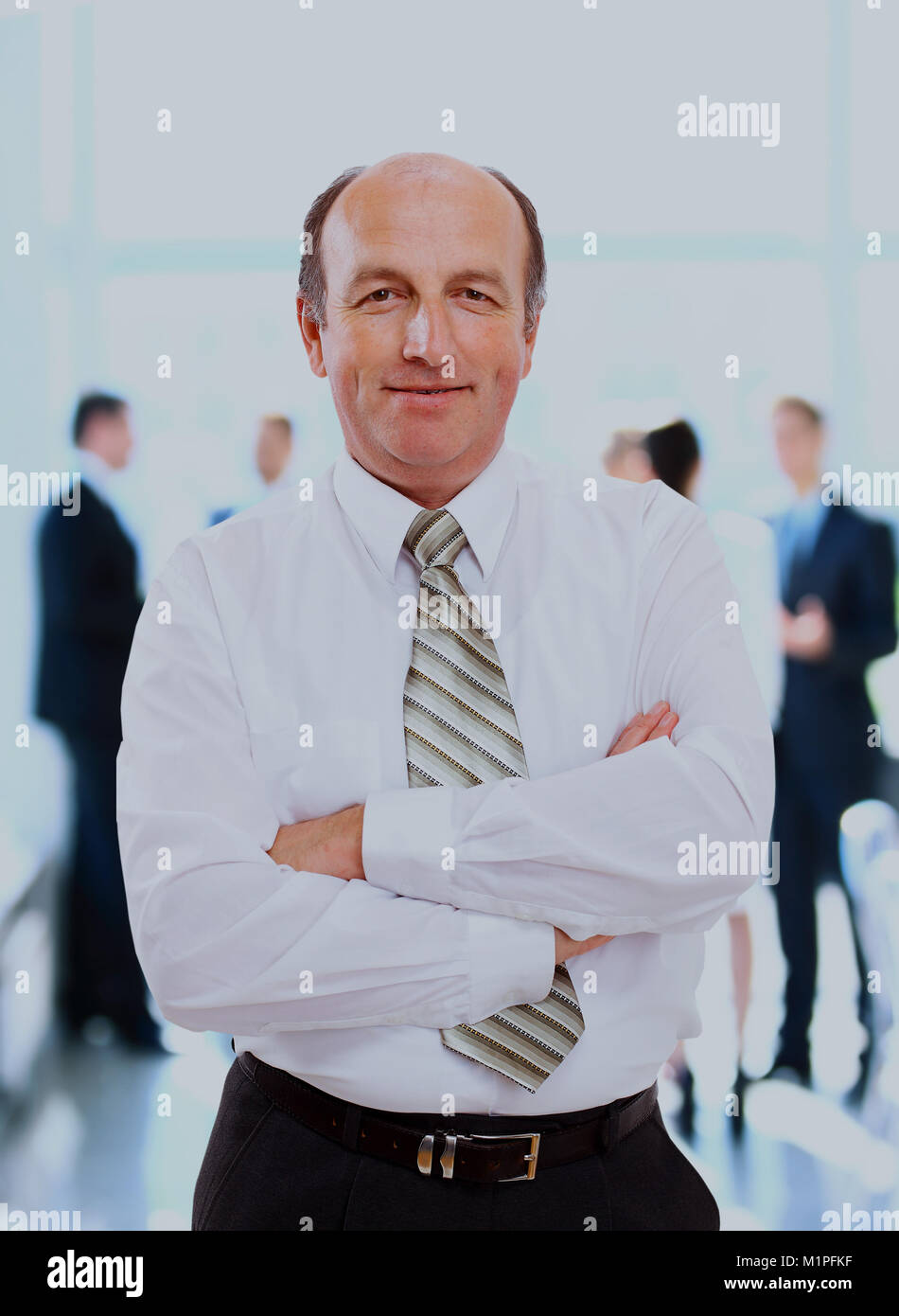 Successful business man standing with his staff in background at office ...