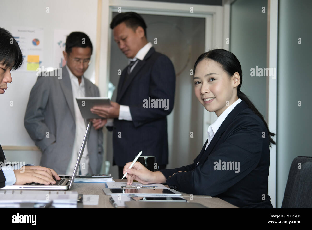 asian businesswoman smiling at camera while colleagues have meeting at office. businessman ...