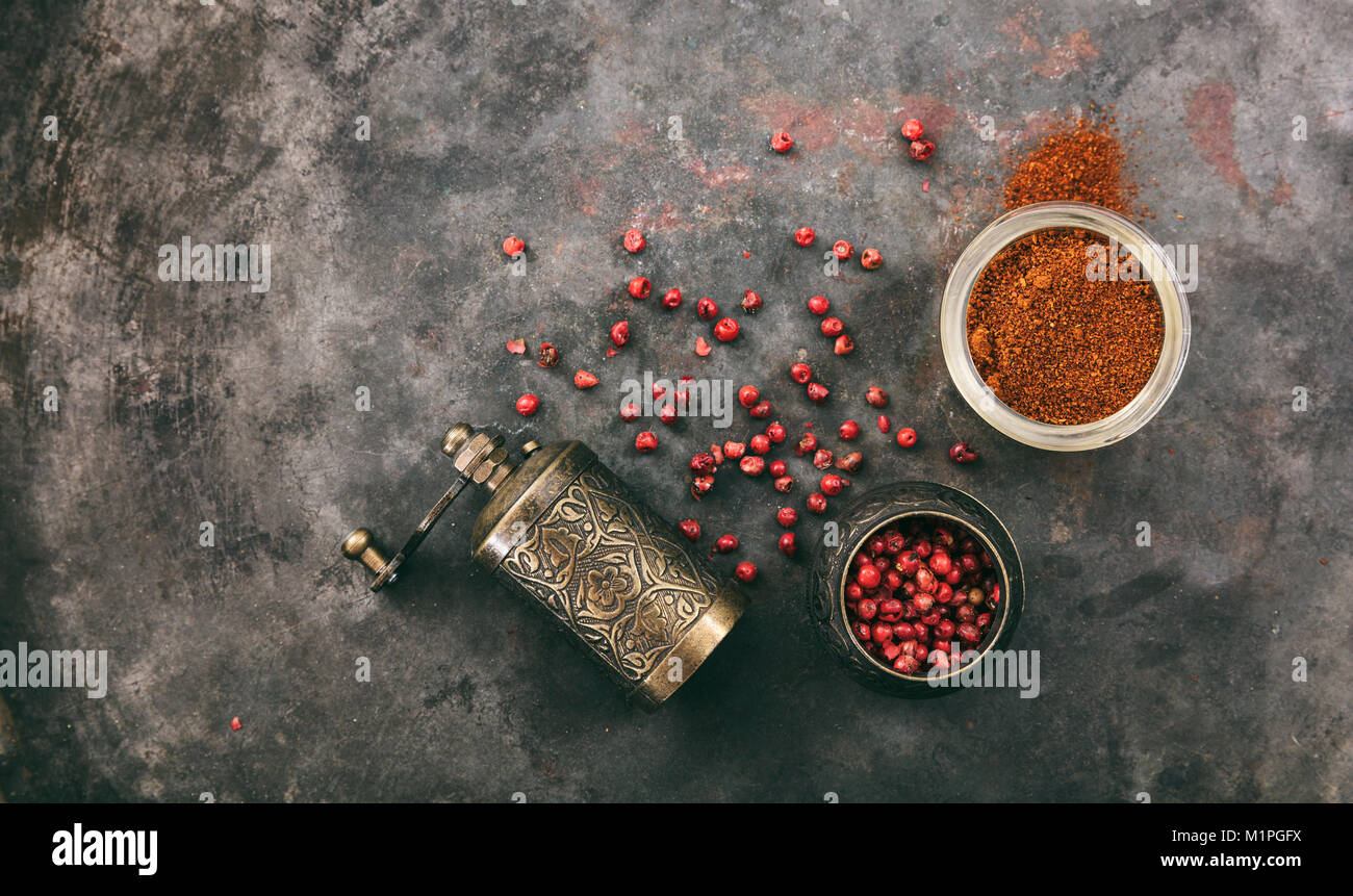 Pink pepper seeds and powder and a brass pepper mill on metal rusty ...