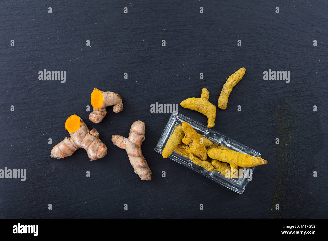 Fresh and dried turmeric or curcumin roots on black background. Top ...