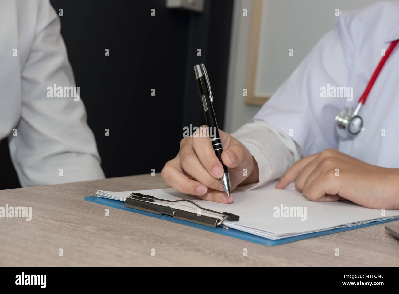 doctor write on medical examination or prescription note at hospital ...