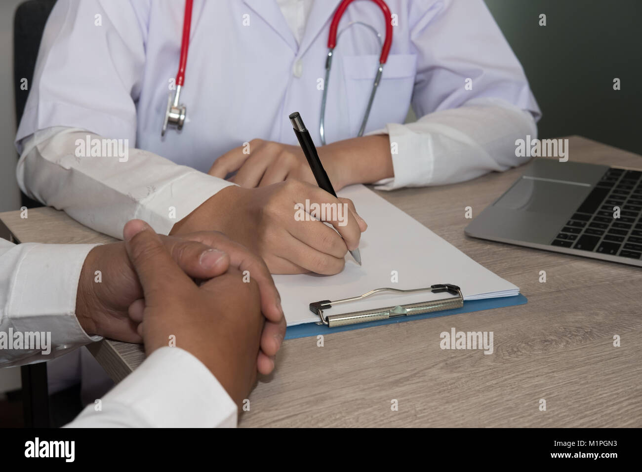 doctor write on medical examination or prescription note at hospital ...