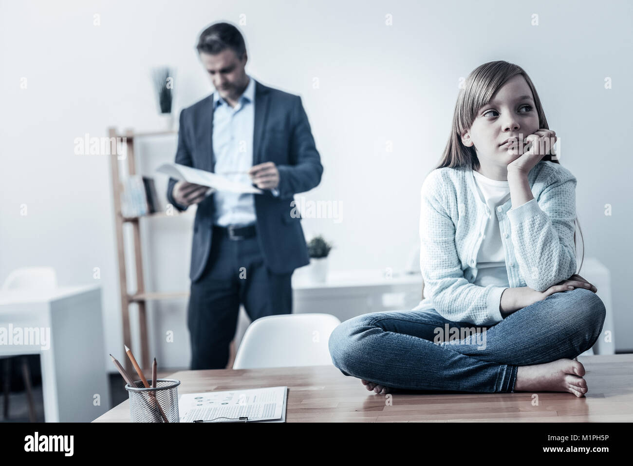 Sad girl missing her daddy busy working in background Stock Photo - Alamy