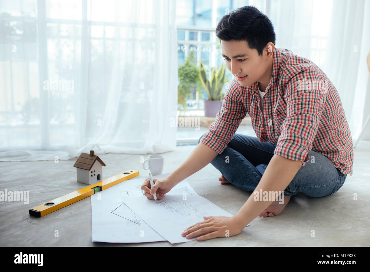 Young handsome male asian architect working at home on the floor Stock ...