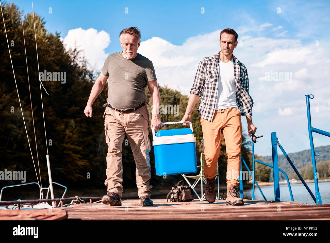 Two men carrying their coolbox Stock Photo - Alamy
