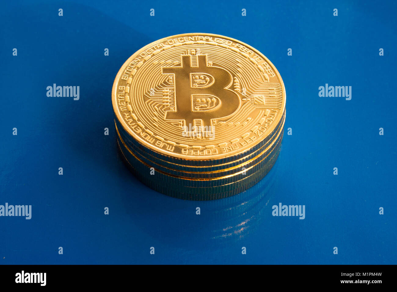 On a blue glass background are gold coins of a digital crypto currency ...