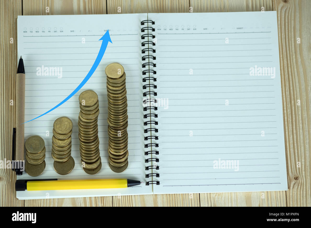 Steps of coins stack with notebook paper on wooden working table with ...