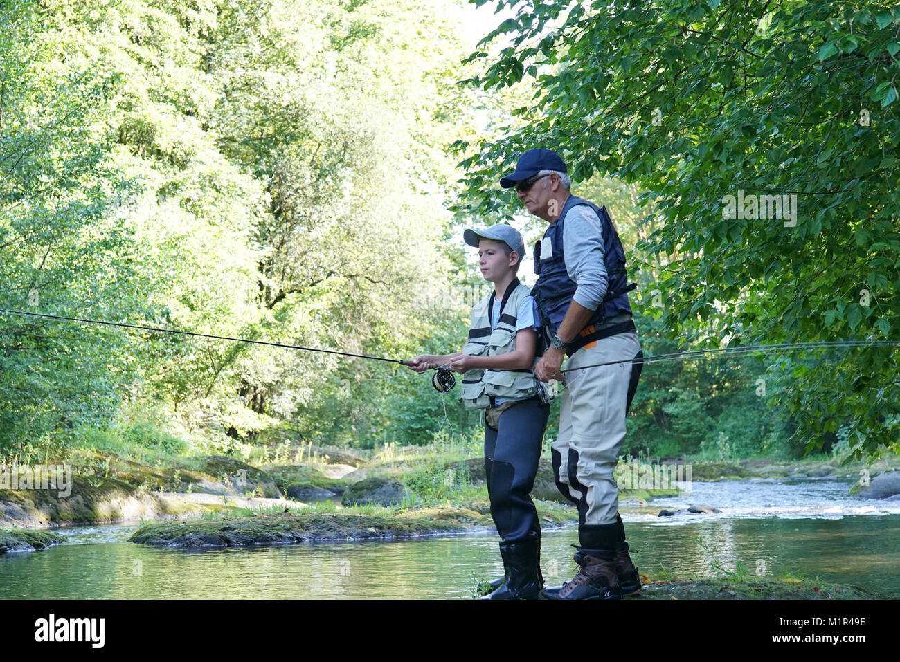 Dad with young boy fly-fishing in river Stock Photo - Alamy