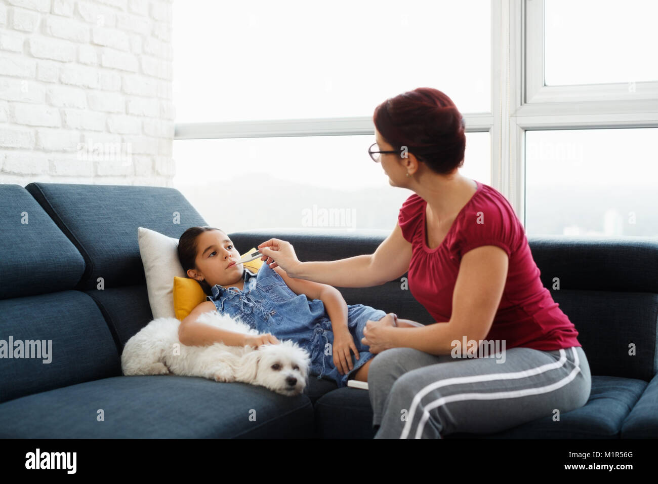 Hispanic mom measuring fever to sick daughter with digital thermometer ...