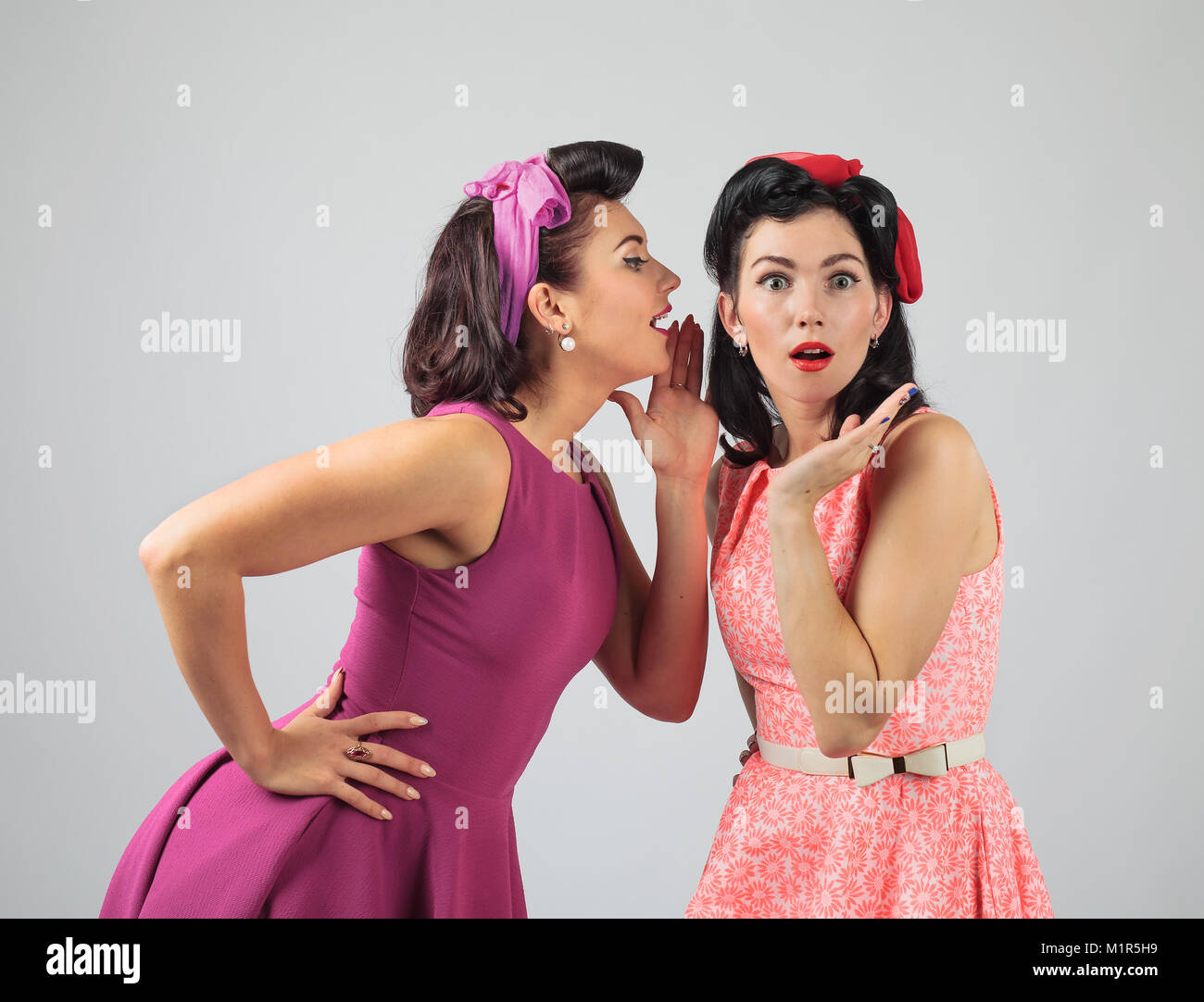 Two young women whispering gossip . Expressive emotion , Studio shot ...