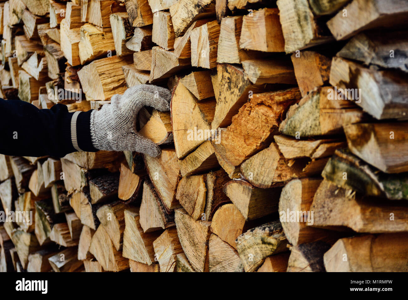 Man hand taking firewood from woodpile Stock Photo - Alamy