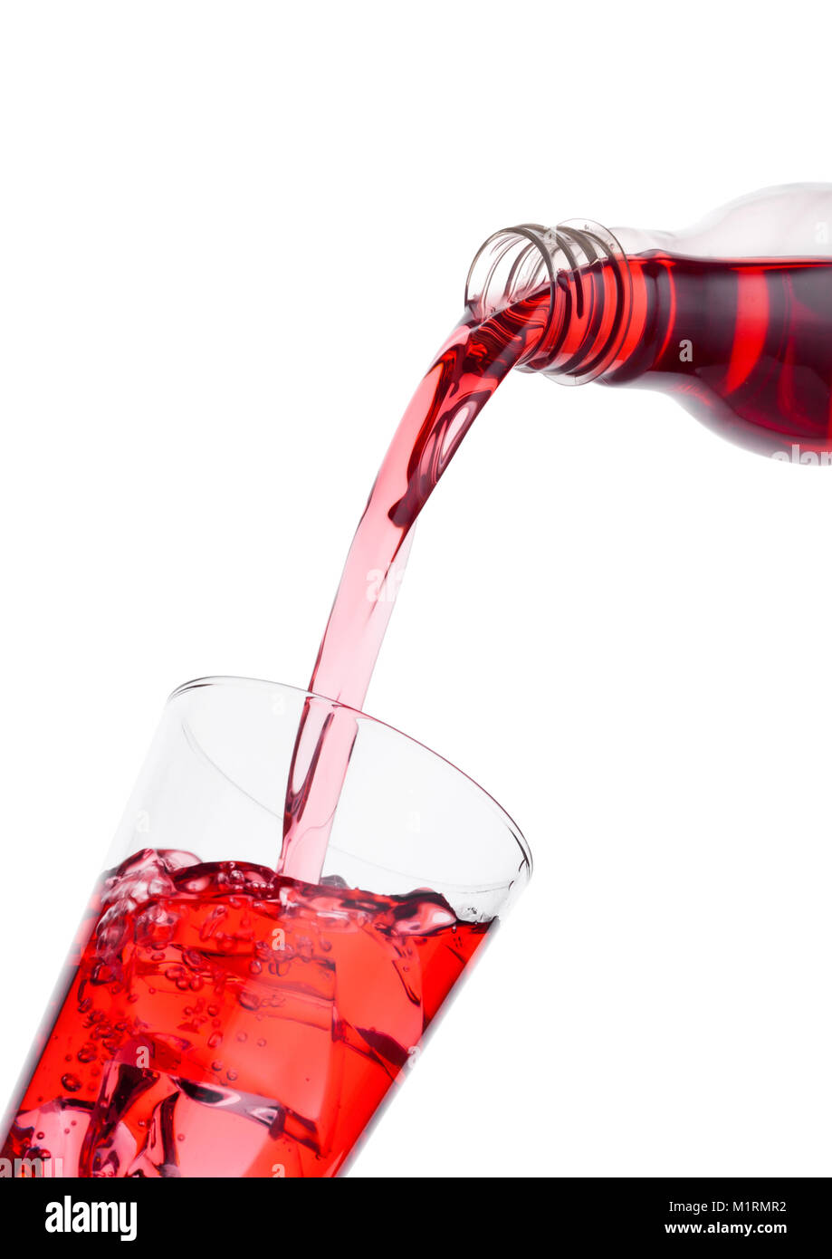 Pouring cranberry red juice from bottle to glass on white background ...