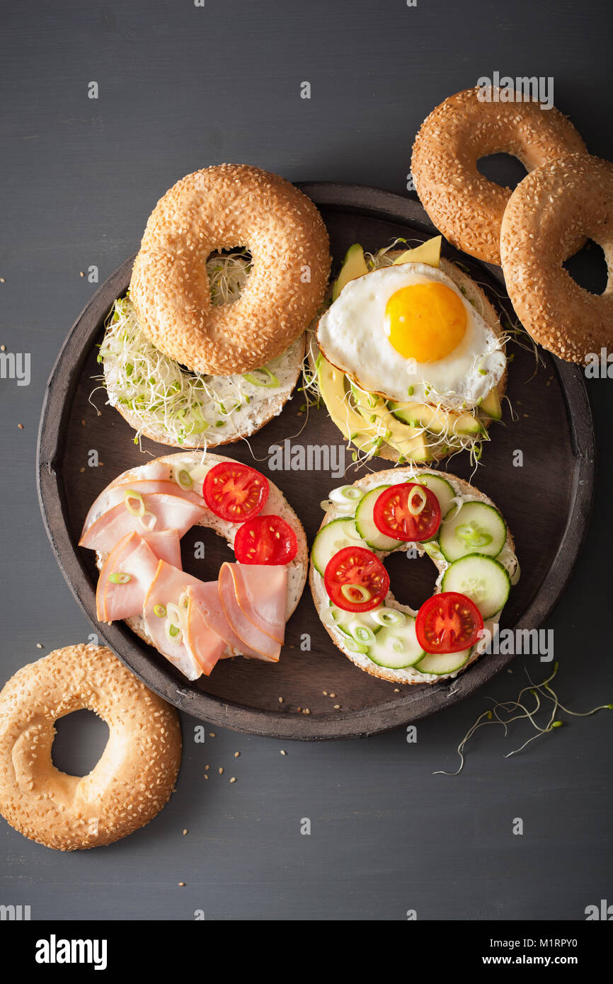variety of sandwiches on bagels: egg, avocado, ham, tomato, soft cheese ...
