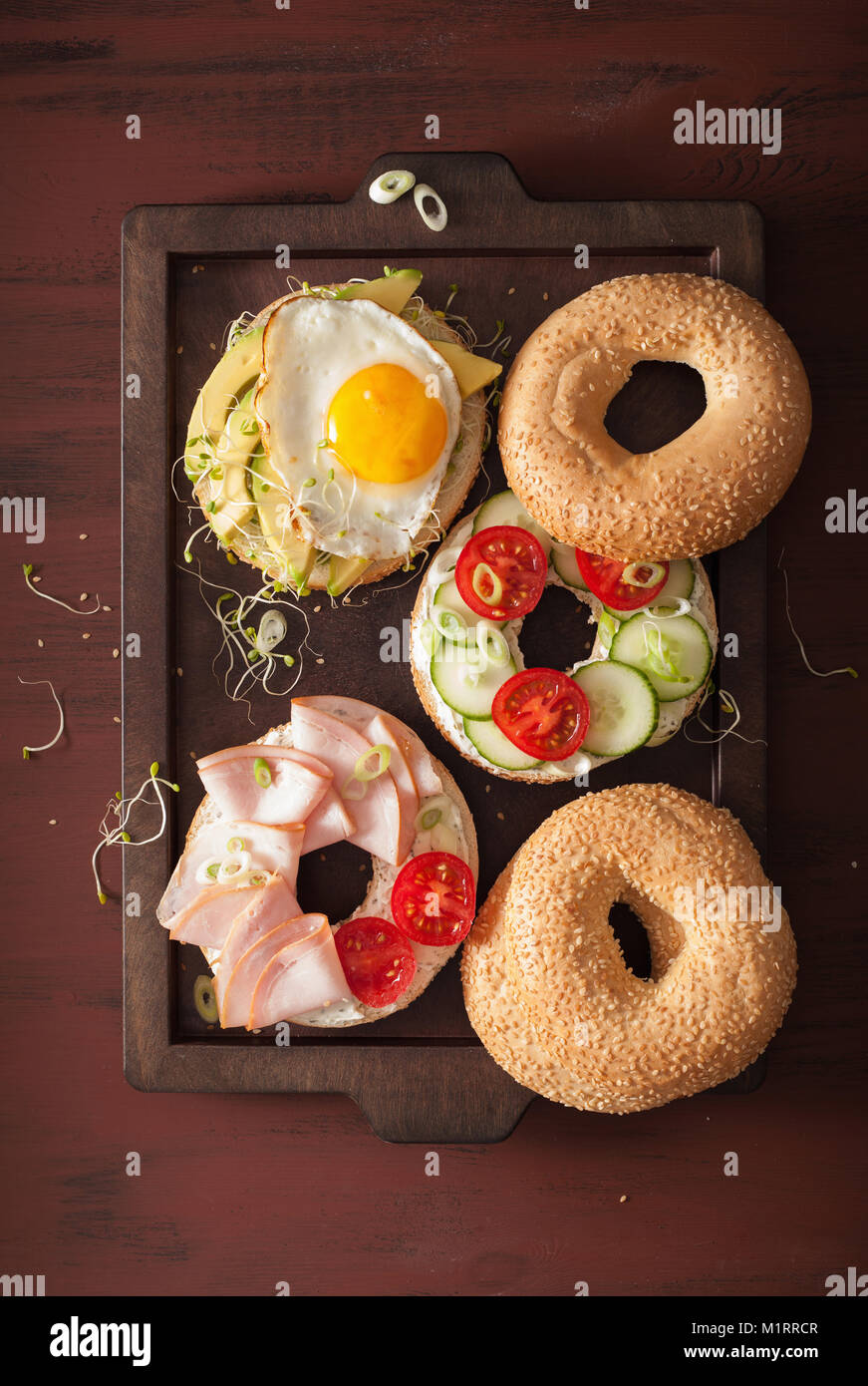 variety of sandwiches on bagels: egg, avocado, ham, tomato, soft cheese ...