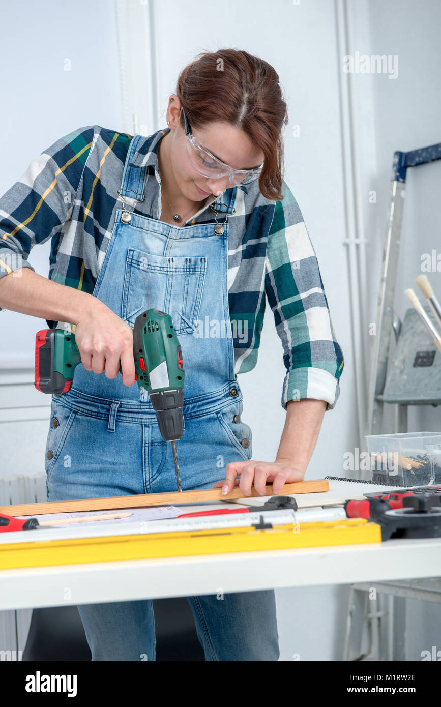 a pretty young smiling woman using cordless drill Stock Photo - Alamy