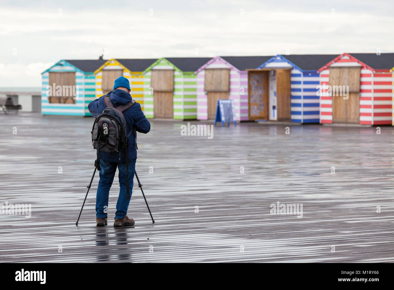 A man with a tripod takes a picture of the hastings beach huts on the ...