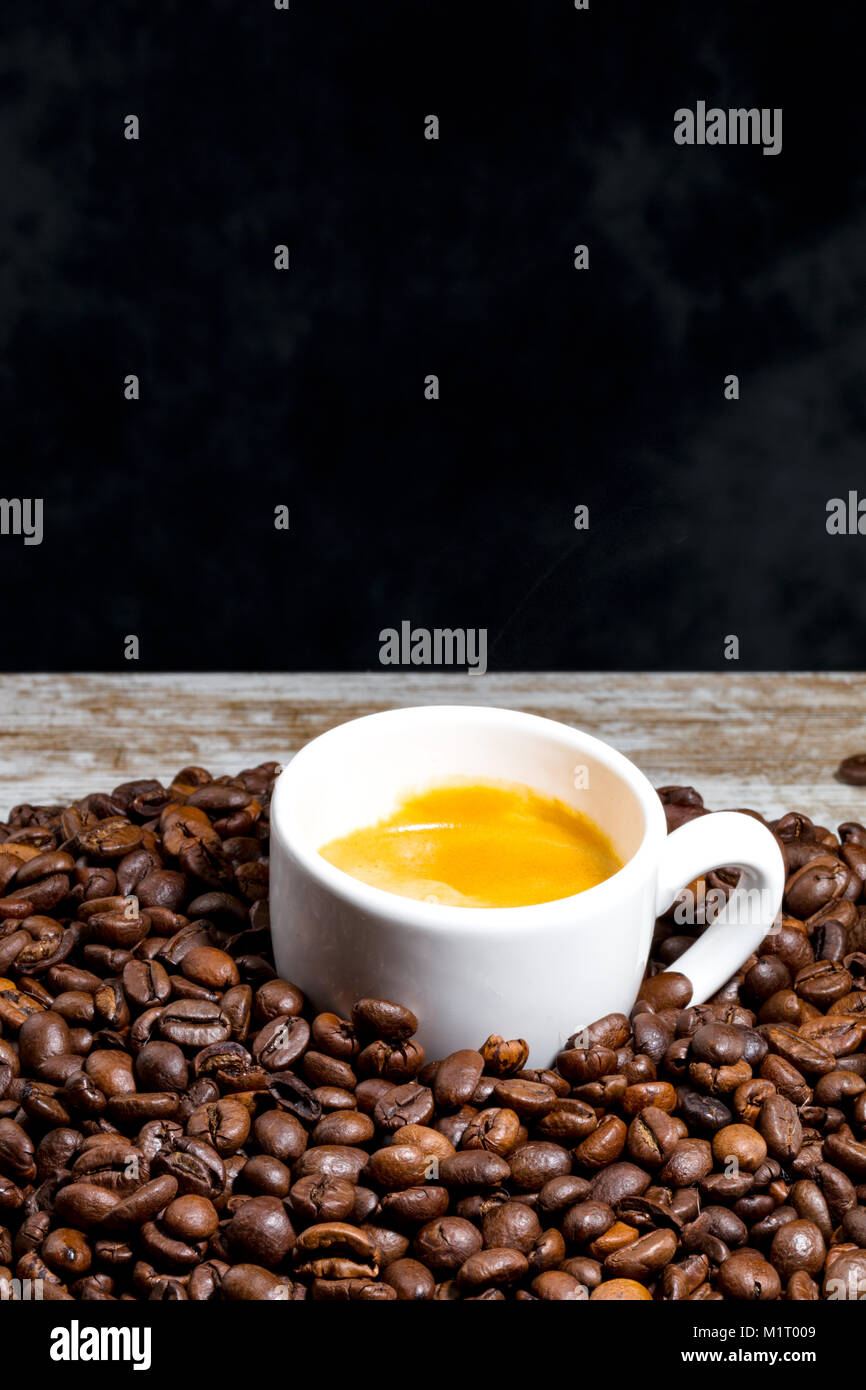 white cup of coffee, just done, on roasted coffee beans, free space for ...