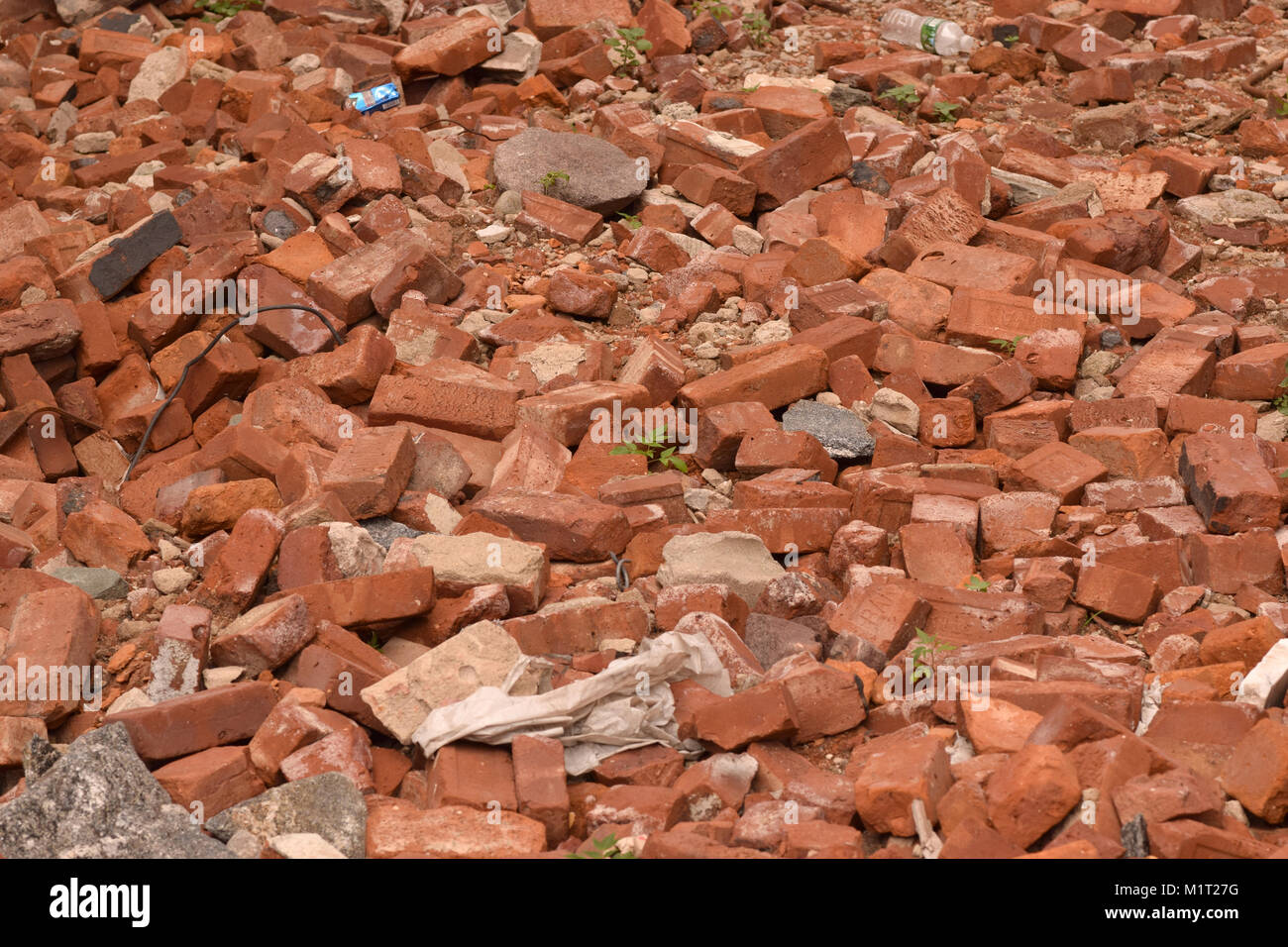 Pile of red bricks and debris with weeds close up abstract texture ...