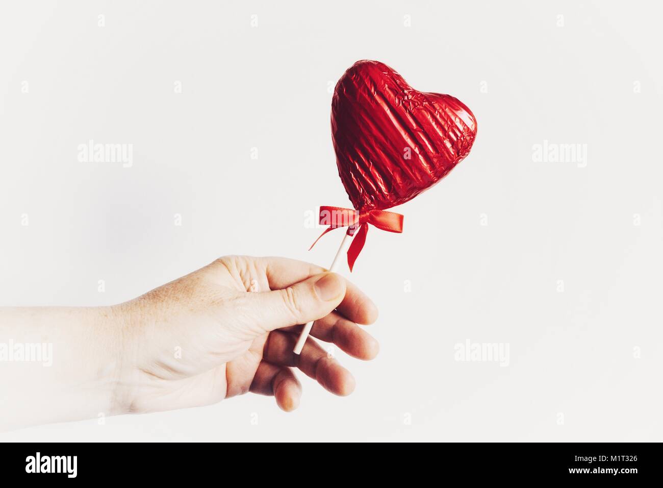 Woman holding a red foil wrapped chocolate lollipop, a special gift for ...