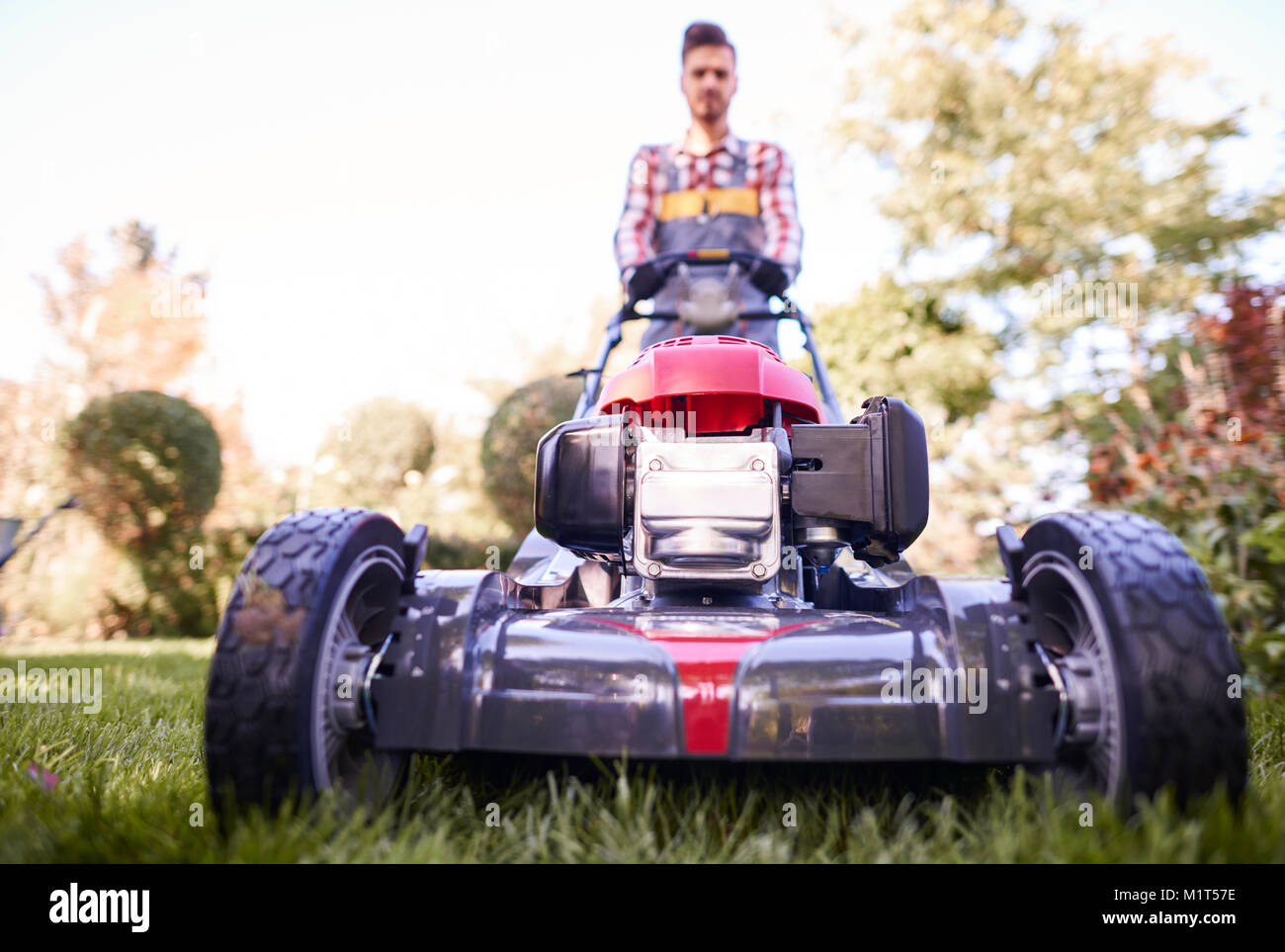 Defocused gardener pushing modern mower Stock Photo - Alamy