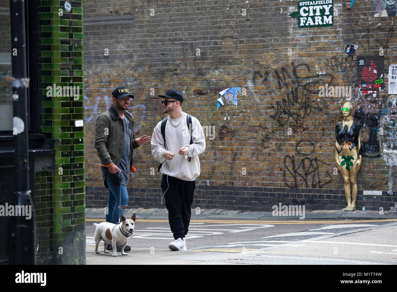 LONDON, ENGLAND - AUGUST 22, 2017 Two young men with a dog talking at ...