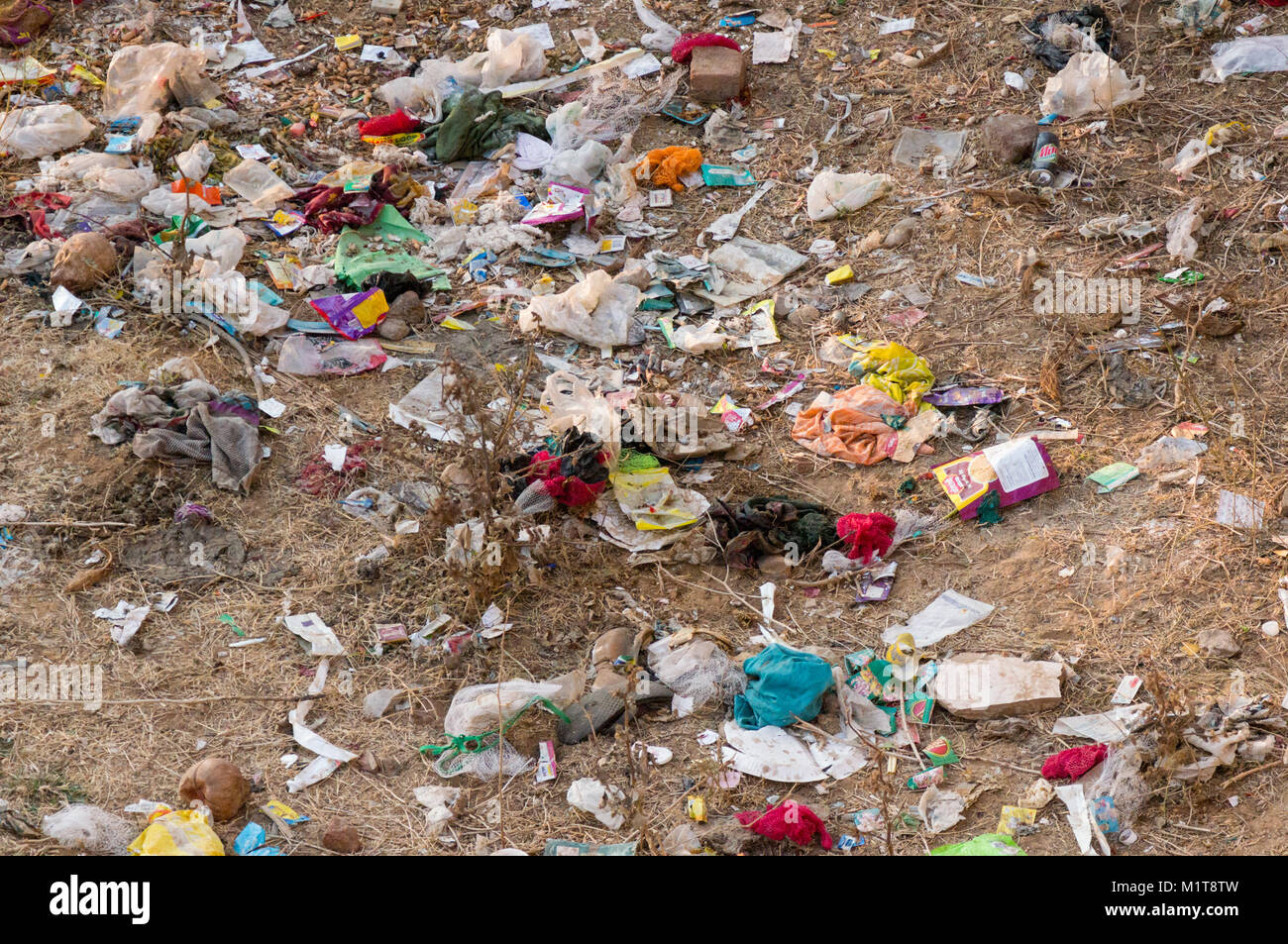 Garbage on mud with wrappers, plastic and paper Stock Photo - Alamy